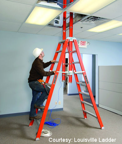 Employee using a trestle ladder to work in an office ceiling.