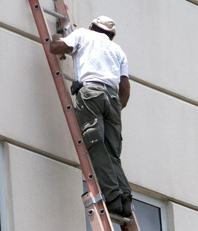 Worker standing on an extension ladder.