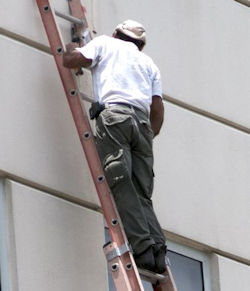 Worker standing on an extension ladder.