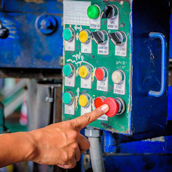 Employee pressing buttons and switches on control panel.
