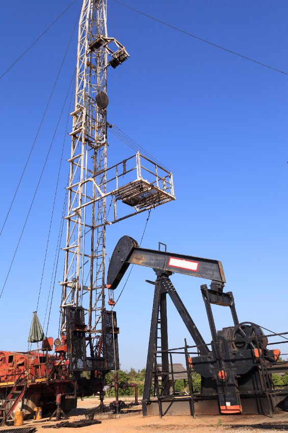 Oil pump jack (sucker rod beam) being serviced by a workover rig